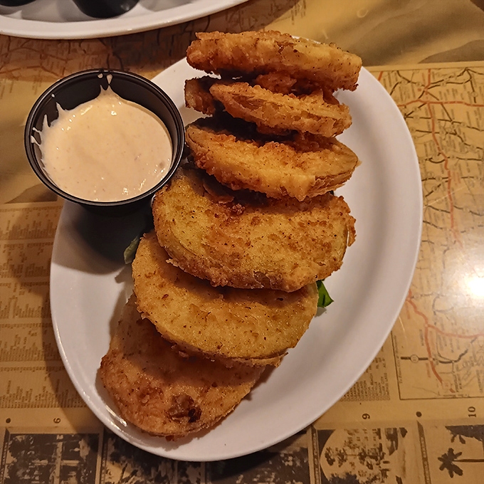 Fried green tomatoes stacked like golden coins, with a side of creamy dipping sauce that makes sharing these nearly impossible.