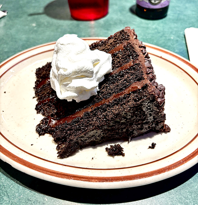 Chocolate cake that makes you reconsider your relationship with dessert. The whipped cream isn't decoration&mdash;it's a necessary cooling system for this decadence.