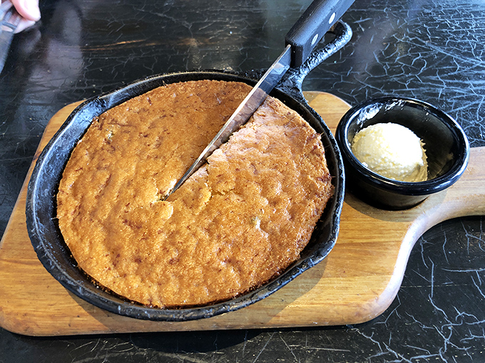 Jalapeño cornbread that arrives sizzling in its own skillet. Crispy edges, tender center, and a pat of butter melting seductively on top.