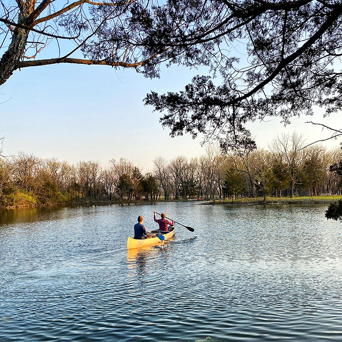 Two paddlers glide across mirror-like waters at golden hour, finding that perfect Kansas silence that's worth more than gold in our noisy world.