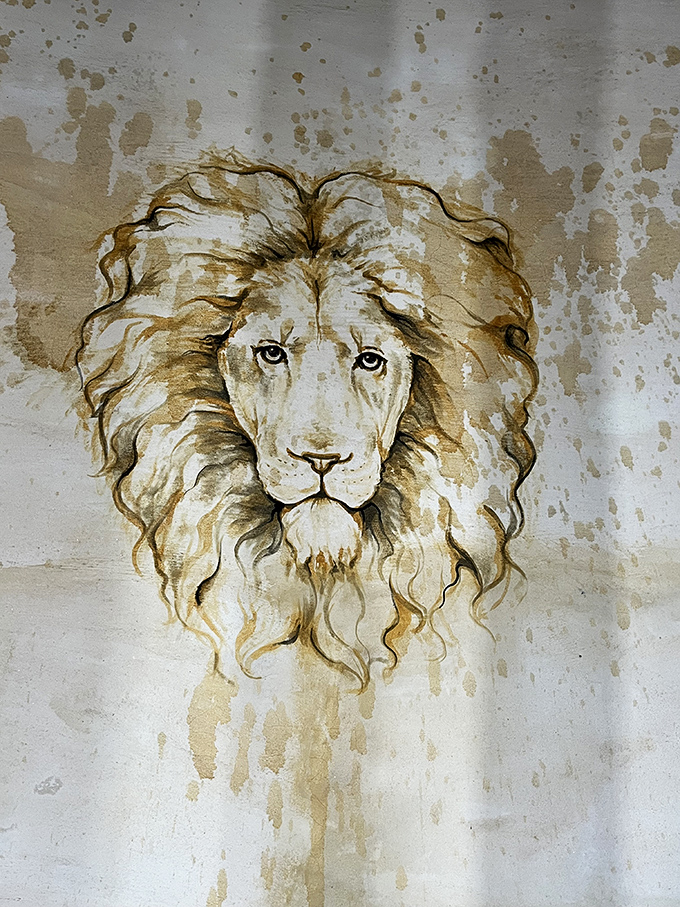 This haunting lion painting seems to emerge from the wall itself, its golden mane and watchful eyes adding mystical presence to the stone interior.