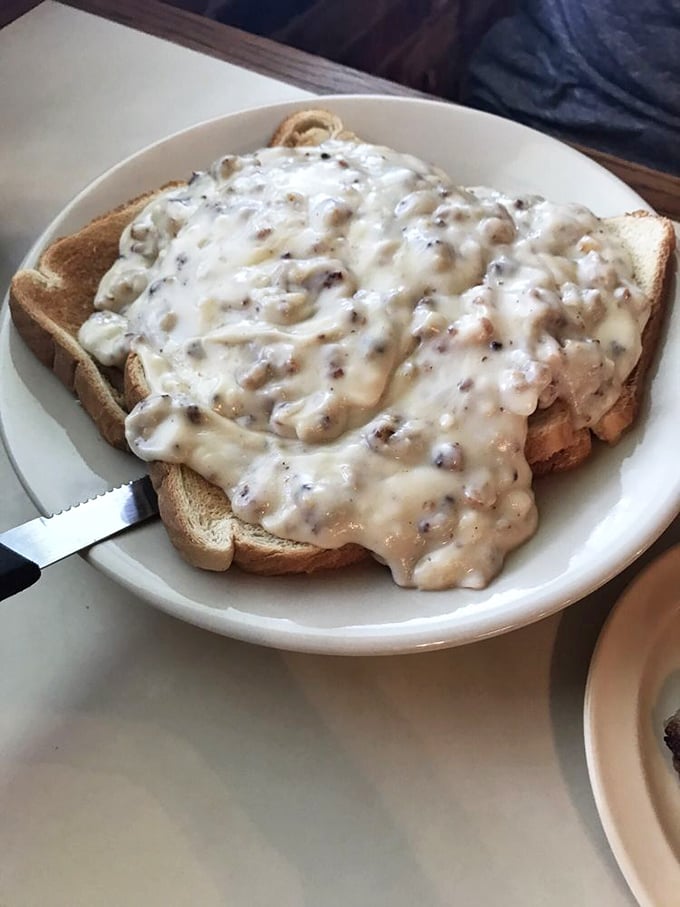 Sausage gravy cascading over toast like a creamy waterfall of breakfast bliss&mdash;cardiologists hate this one simple trick for happiness.