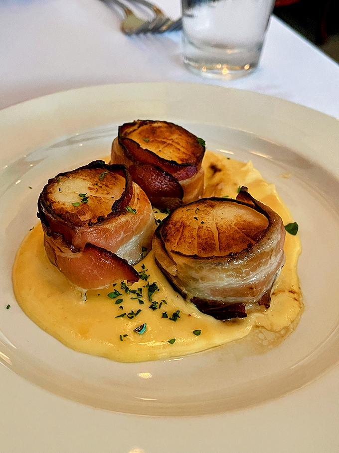 Bacon-wrapped scallops that make you question why we don't wrap everything in bacon, presented on a pool of sauce that begs to be sopped up.