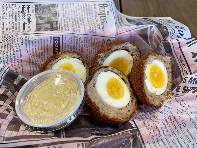 Scotch eggs—where sausage hugs hard-boiled eggs in a warm, crispy embrace—served properly on newspaper like the British culinary gods intended.