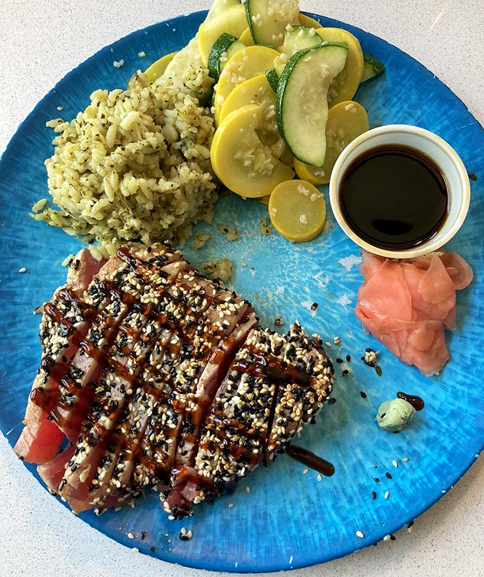 Sesame-crusted ahi tuna that's barely kissed the heat. The rice looks like it's been seasoned by someone who knows what they're doing.
