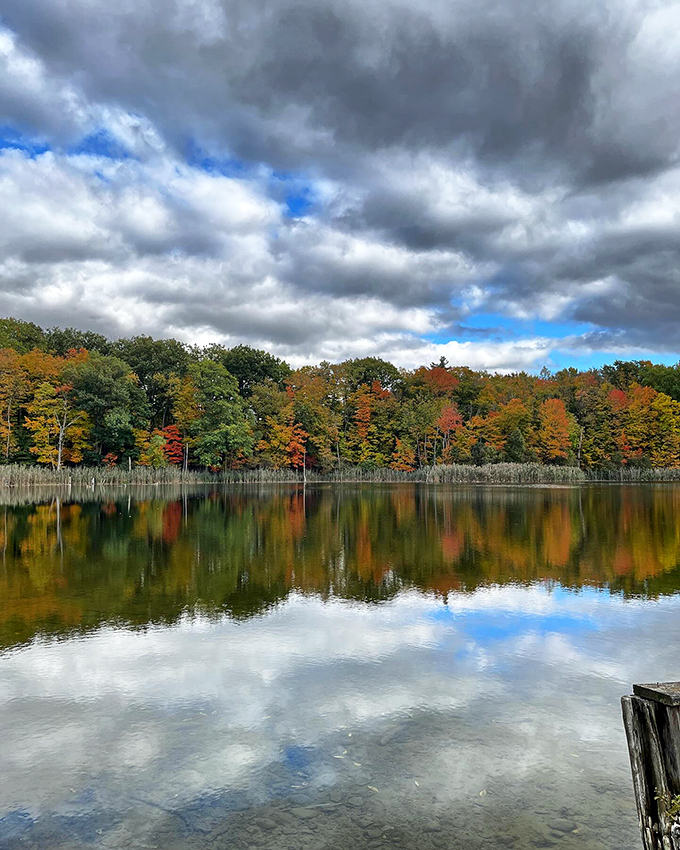 Fall foliage reflects perfectly in still waters, creating nature's version of Instagram filters long before social media made everything "content."