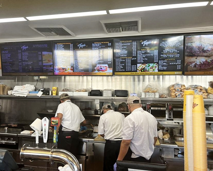 The white-capped kitchen crew moves with the choreographed precision of a culinary ballet. These are the unsung heroes of your lunch satisfaction.