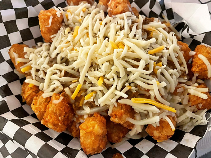 Tater tots reach their final glorious form under a snowfall of shredded cheese, transforming humble potatoes into a monument to indulgence.