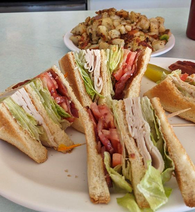 Turkey club sandwich towering with fresh ingredients, proving lunch here rivals the breakfast reputation completely.