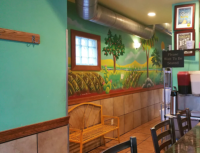The waiting area's hand-painted mural transforms a simple corner into a Mexican countryside vista. Even waiting for a table becomes part of the experience.