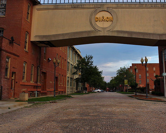 The DIMON archway frames a cobblestone street vista, where converted tobacco warehouses now house apartments, shops, and restaurants in industrial-chic splendor.