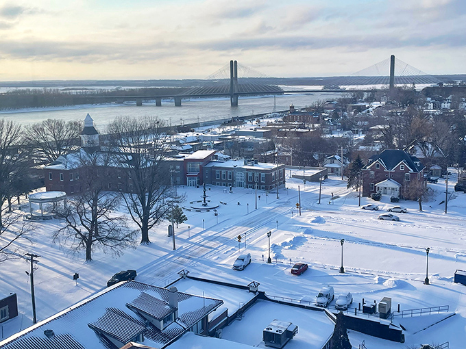 Winter transforms Cape Girardeau into a snow globe scene, with the river and bridge creating a dramatic backdrop to the peaceful white landscape.