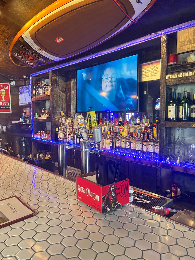 A bar stocked with enough spirits to raise a pirate ship, all illuminated by blue lights that make every bottle look like underwater treasure.