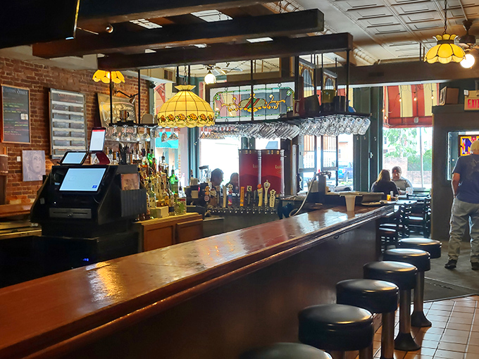 Stained glass pendant lights cast a golden glow over the wooden bar, where stools await those seeking libations with their comfort food fix.