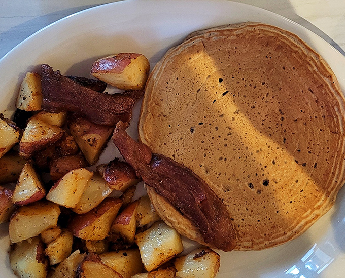 A perfectly golden pancake with a side of potatoes and bacon&mdash;the holy trinity of breakfast that's worth setting your alarm for.