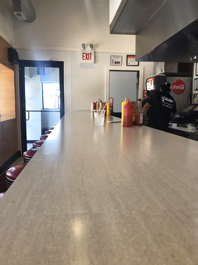The counter stretches like a runway where breakfast dreams take flight. Those condiment bottles have witnessed countless conversations between strangers turned friends.