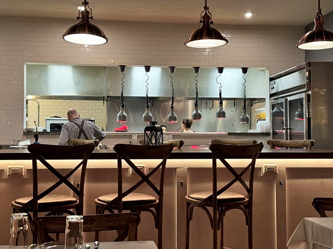 The open kitchen offers dinner and a show, where culinary magic happens under copper pendant lights that cast a warm glow over the proceedings.