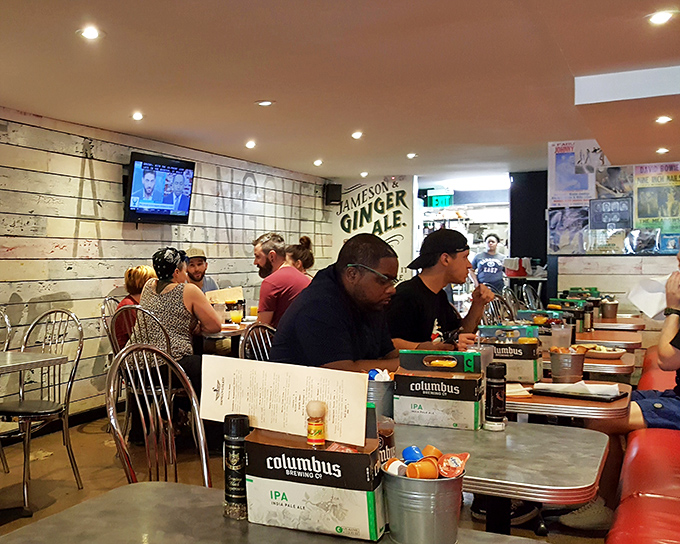 The tables might be metal, but the atmosphere is pure warmth. Columbus craft beer boxes serve as clever table centerpieces in this university-adjacent haven.