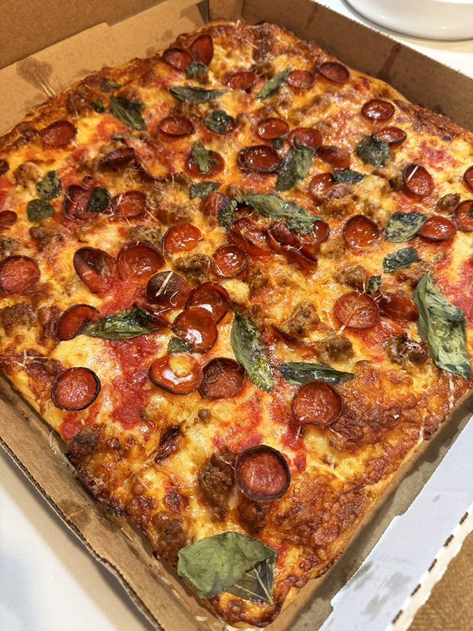 The Grandma Pie in all its square-cornered glory. Crispy-edged perfection topped with pepperoni cups that have crisped into flavor vessels, with fresh basil adding color and aroma.