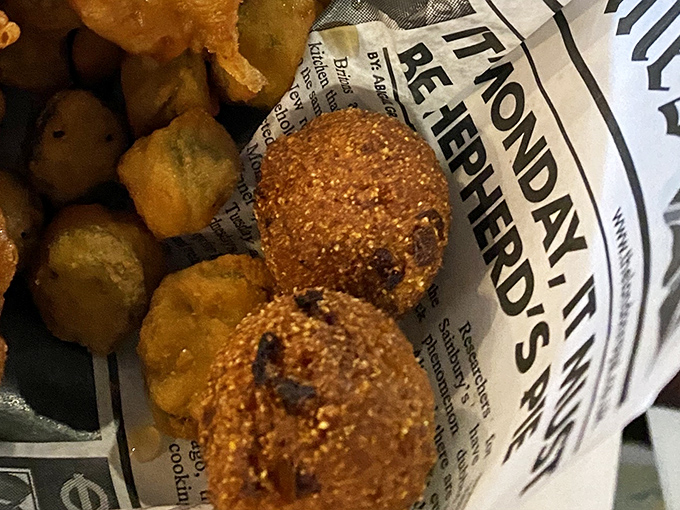 Hush puppies nestled against newspaper &ndash; Southern comfort meets British tradition in these golden-fried spheres of happiness.