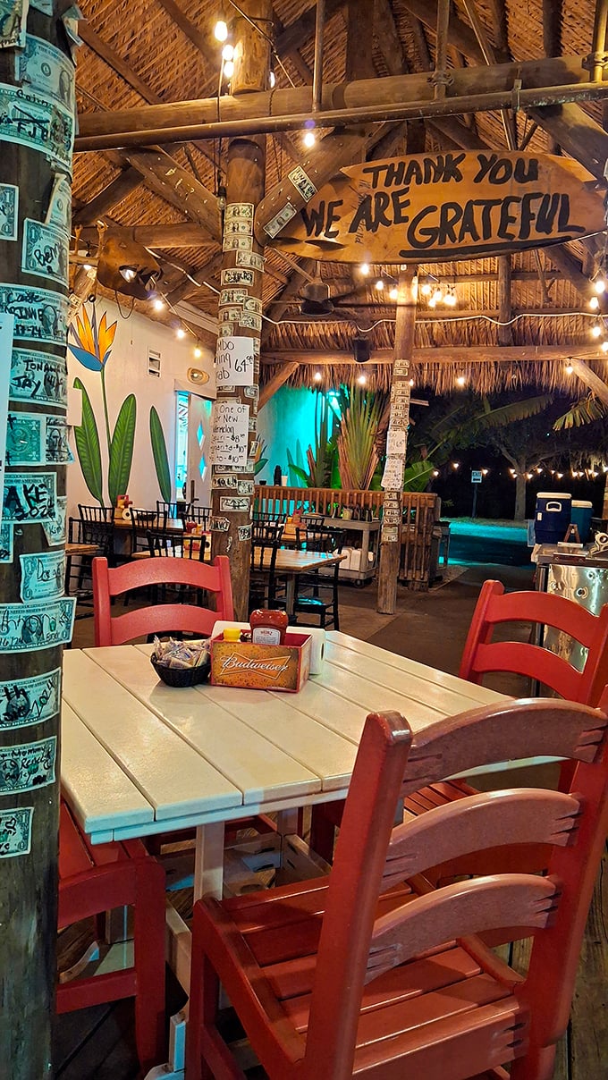 Dollar bills papering wooden posts under a thatched roof create the ultimate "I'm on vacation" vibe in this grateful outdoor dining sanctuary.
