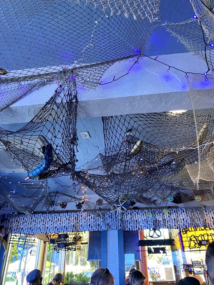 The ceiling's fishing net canopy, adorned with twinkling lights and sea treasures, makes you feel like you're dining under the ocean.