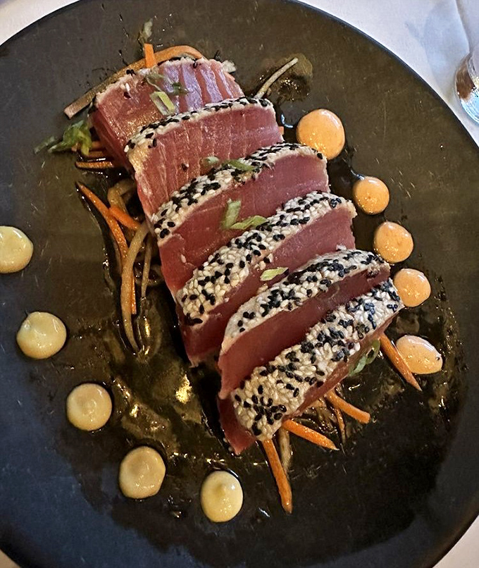 Seared tuna arranged with surgical precision, surrounded by sauce dots that look like they're applying for art school admission.