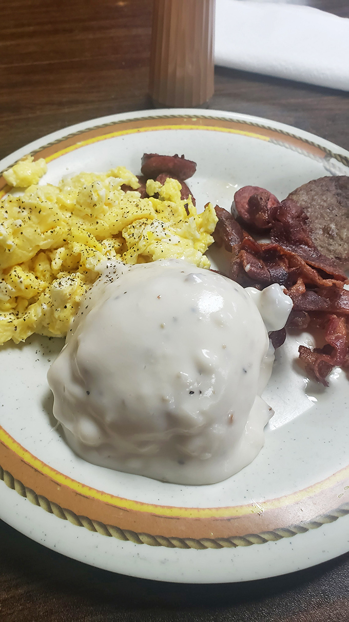 The holy trinity of breakfast: perfectly scrambled eggs, crispy bacon, and a biscuit smothered in country gravy that could end wars.