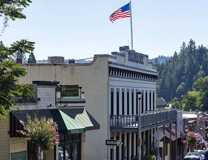 An American flag waves proudly above historic buildings, where gold rush dreams have evolved into small-town success stories that continue today.