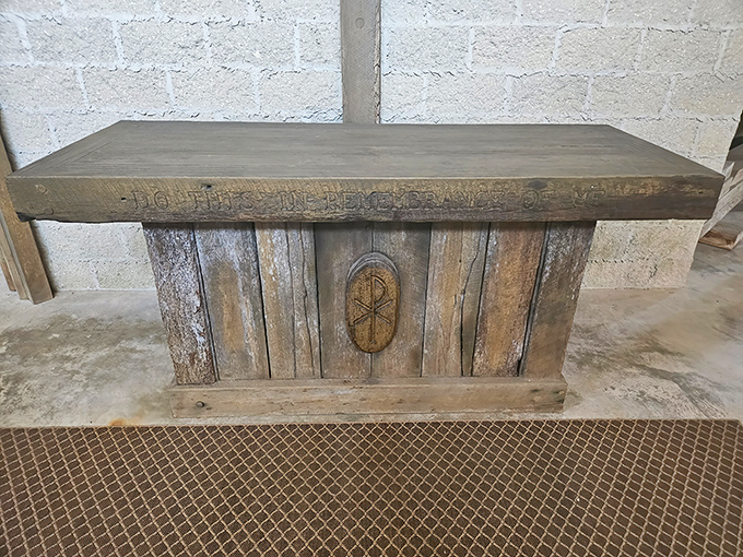 "Do this in remembrance"&mdash;the altar's weathered wood and simple inscription speak to the castle's spiritual purpose beyond its medieval appearance.