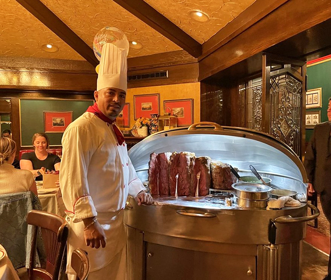 The tableside carving ritual transforms dinner into theater, with the chef as both artist and performer, revealing the rosy interior of perfectly aged beef.