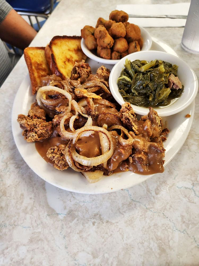 Chicken livers achieve crispy perfection alongside vibrant collard greens and golden-fried okra&mdash;a plate that tells Mississippi's culinary story in one glance.