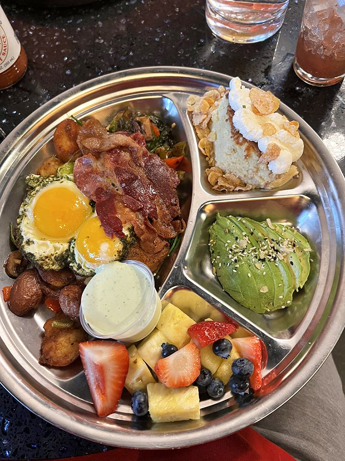 A breakfast that refuses to be boring&mdash;eggs, bacon, roasted vegetables, and sides arranged like a delicious solar system on a metal plate.