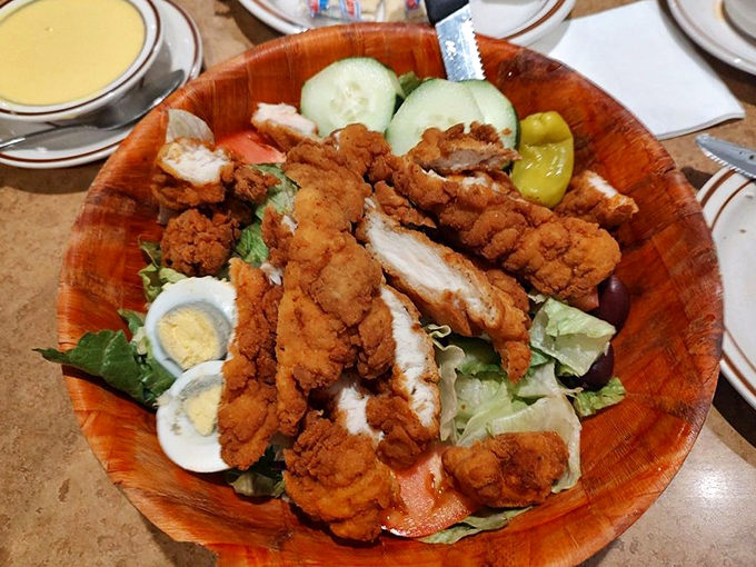 Crispy chicken perched atop garden-fresh greens like the world's most delicious bird's nest. That wooden bowl adds rustic charm.