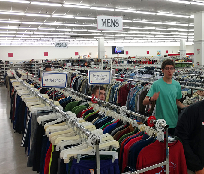 Fellow treasure hunters navigate the well-organized men's section. The thrill of the hunt connects strangers in this community of savvy shoppers.
