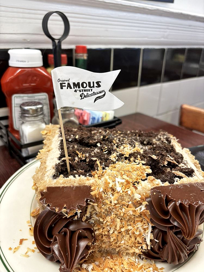 A chocolate cake so decadent it deserves its own zip code, proudly flying the deli's flag like it just conquered Mount Dessert.