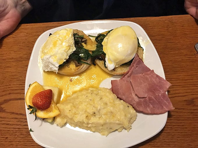 Eggs Benedict done right&mdash;perfectly poached eggs cascade golden yolk over English muffins, with grits and ham completing this Southern breakfast symphony.