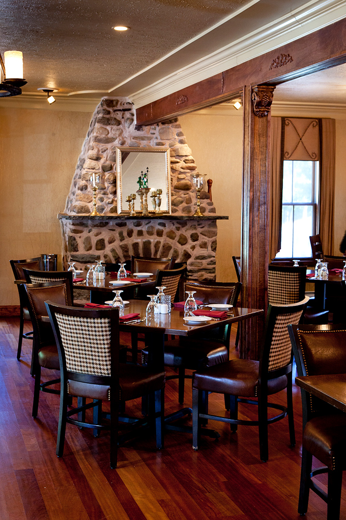 Stone fireplace anchors the dining room with rustic elegance. Checkerboard chairs invite you to settle in and forget about tomorrow's to-do list.