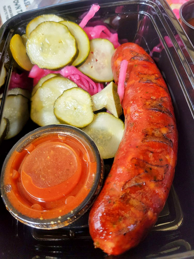 The jalape&ntilde;o sausage poses proudly among pickled vegetables like a spicy celebrity on a vibrant red carpet. That sauce cup is liquid gold.