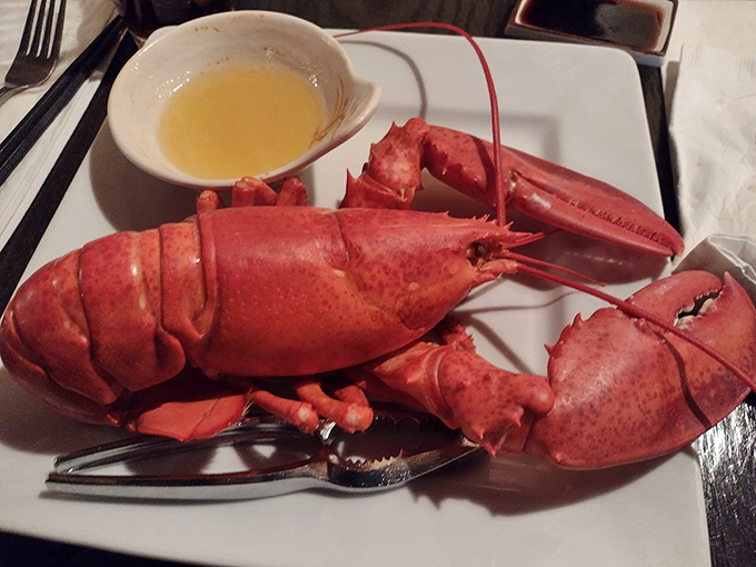 The lobster arrives like royalty on a white plate throne. Breaking into that claw is the culinary equivalent of finding buried treasure. 
