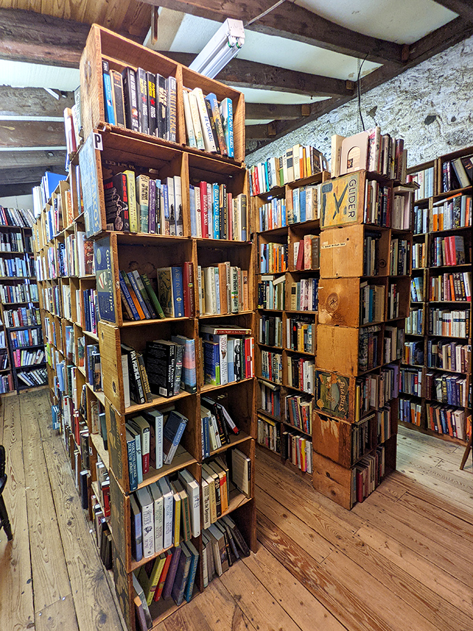 Wooden crates transformed into bookshelves create a charming hodgepodge of literary neighborhoods, where bestsellers and forgotten gems share equal billing.