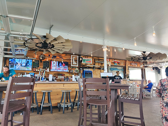 Windmill ceiling fans and wooden walls create the perfect coastal vibe. This bar area invites you to linger over one more drink.