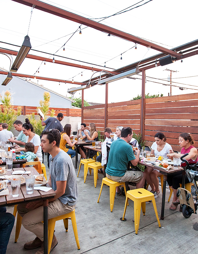 The outdoor patio doesn't just seat diners&mdash;it hosts food pilgrimages. Those yellow stools collect people who've come to worship at the altar of perfect fries.