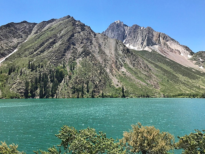 Alpine lake perfection: This emerald-green mountain lake reflects jagged peaks with such clarity it's hard to tell where reality ends and reflection begins.