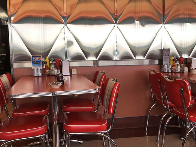 These aren't just chairs; they're front-row seats to the theater of American dining. The stainless steel waves behind them are practically applauding your excellent taste.