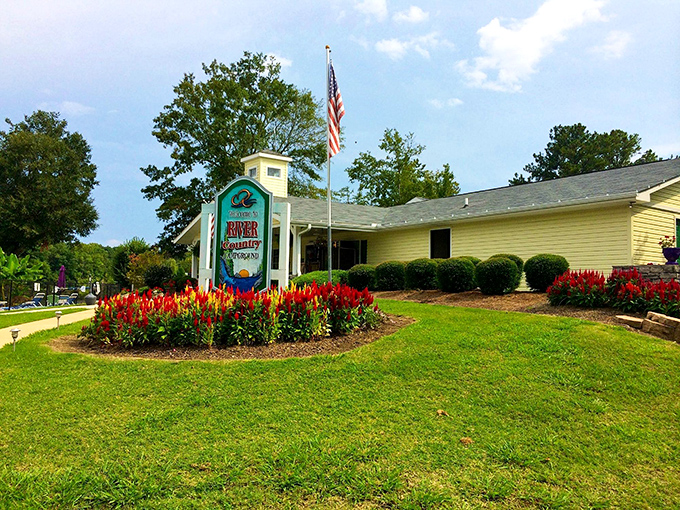 The River Country Campground welcomes outdoor enthusiasts with cheerful signage and flowers as red as Alabama clay, promising riverside adventures for all.