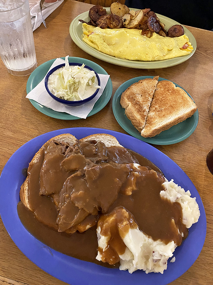 Comfort food royalty: fork-tender roast beef swimming in rich gravy alongside a fluffy omelet that proves breakfast knows no time constraints.