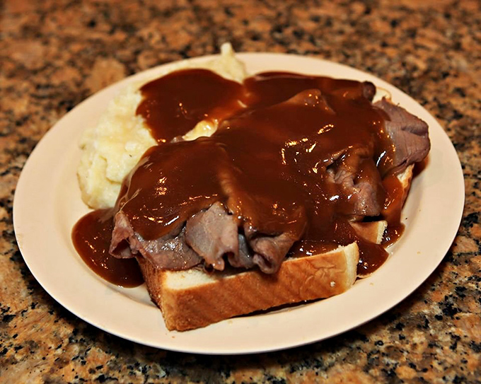 Hot roast beef on white bread with gravy cascading over the sides&mdash;a sandwich so gloriously messy it requires strategic eating and zero shame.