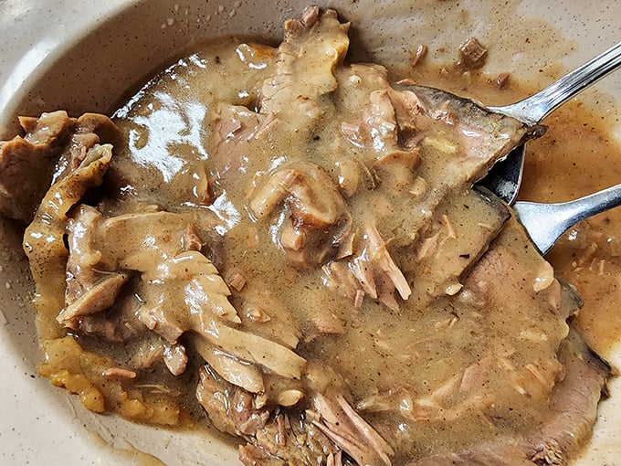 Fork-tender roast beef swimming in rich gravy that's destined for a rendezvous with those fluffy mashed potatoes waiting just out of frame.