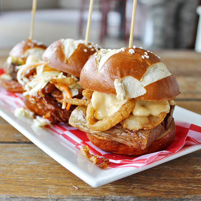 These aren't ordinary sliders &ndash; they're pretzel-bunned flavor bombs, where crispy onions and melty cheese create the perfect German-American love story.